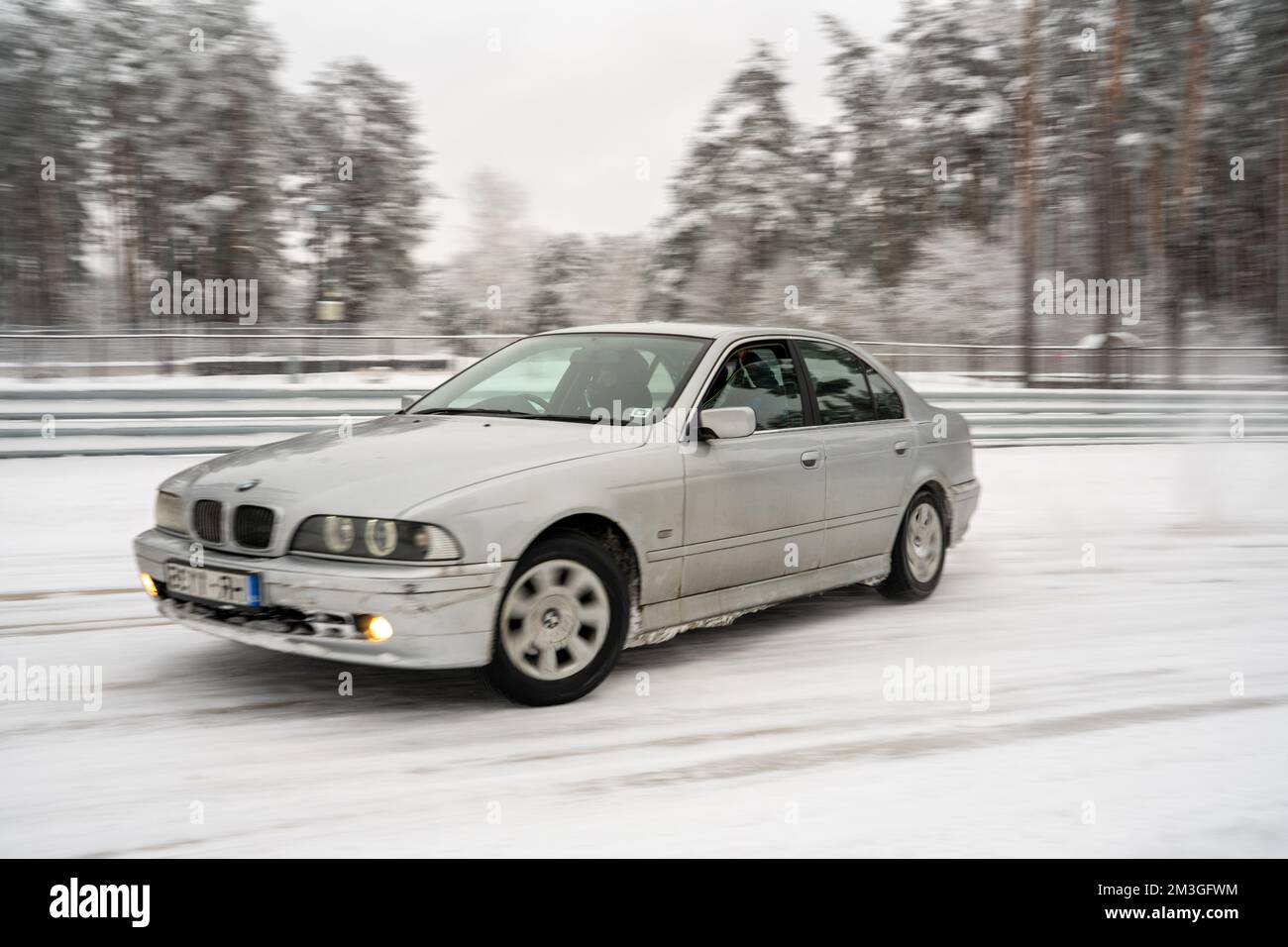 12-12-2022 Riga, Latvia a white car driving down a snowy road next to ...