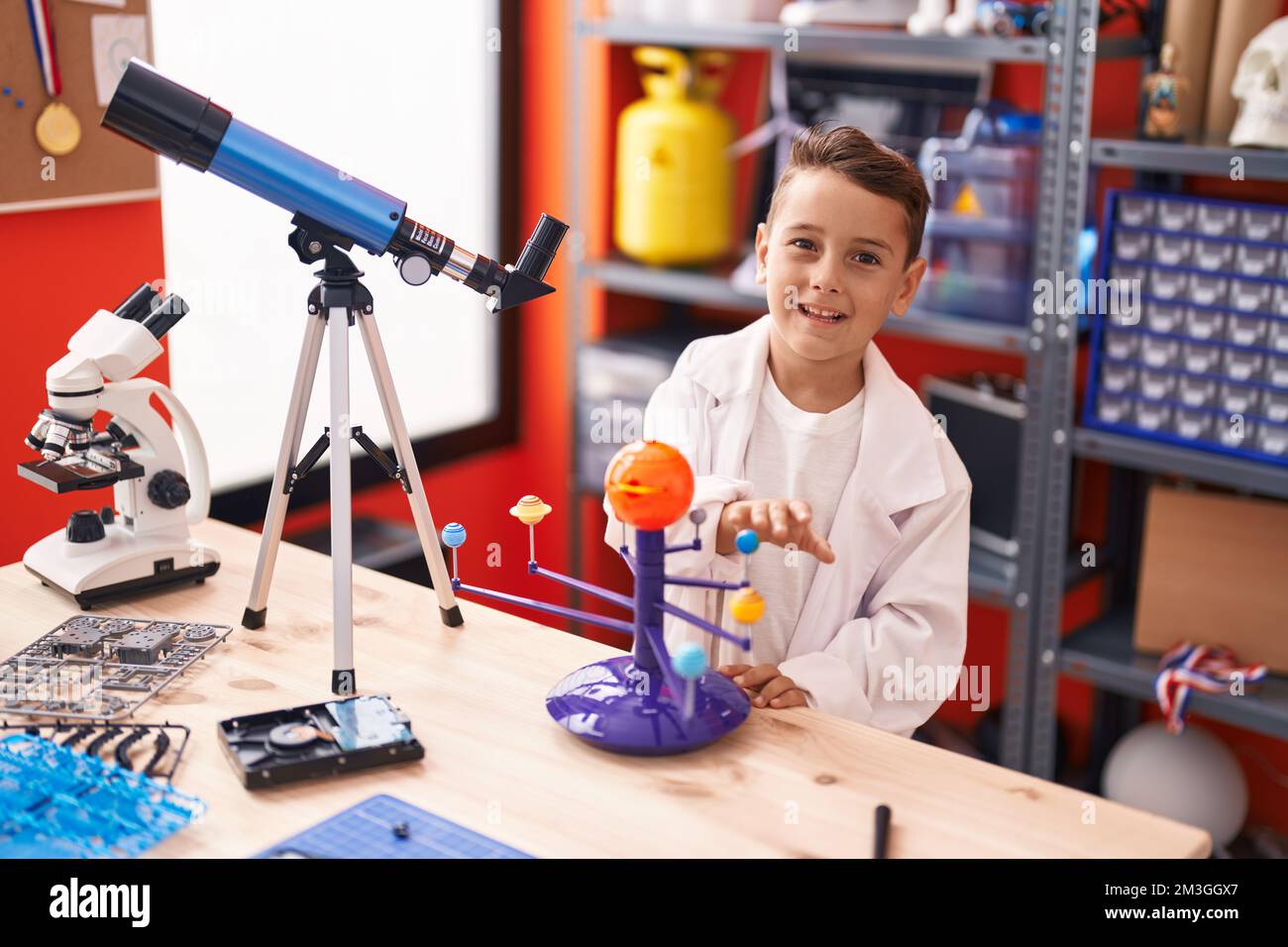 Adorable hispanic toddler student smiling confident using telescope at ...