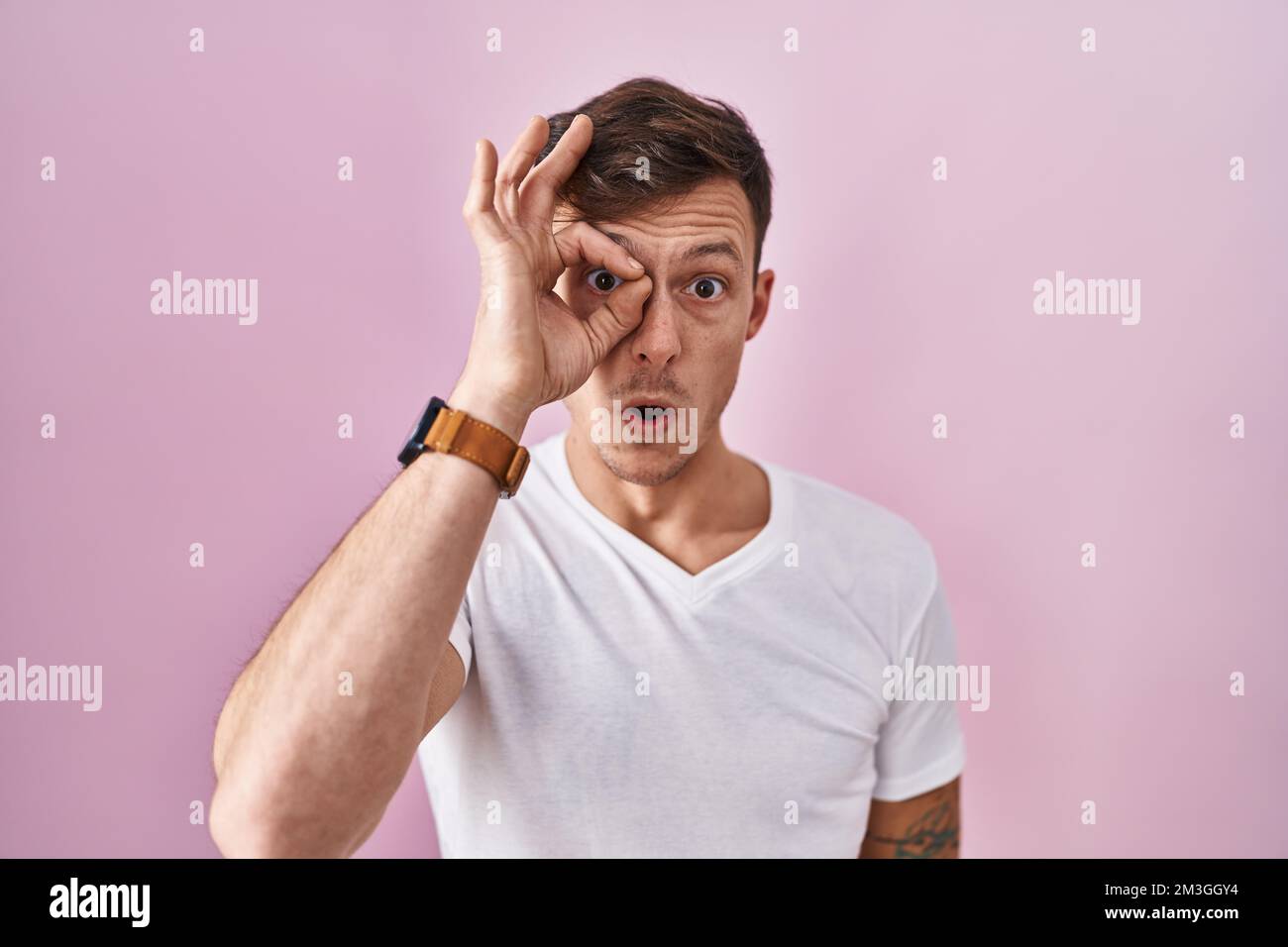 Caucasian man standing over pink background doing ok gesture shocked ...