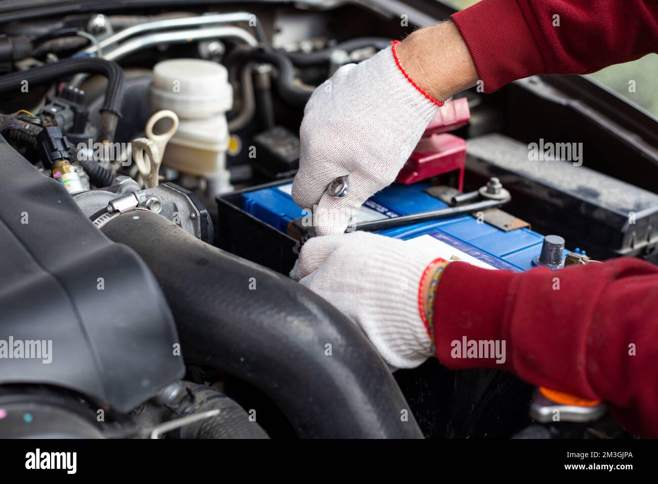 car mechanic repairing a car. A man replaces a car battery Stock Photo ...