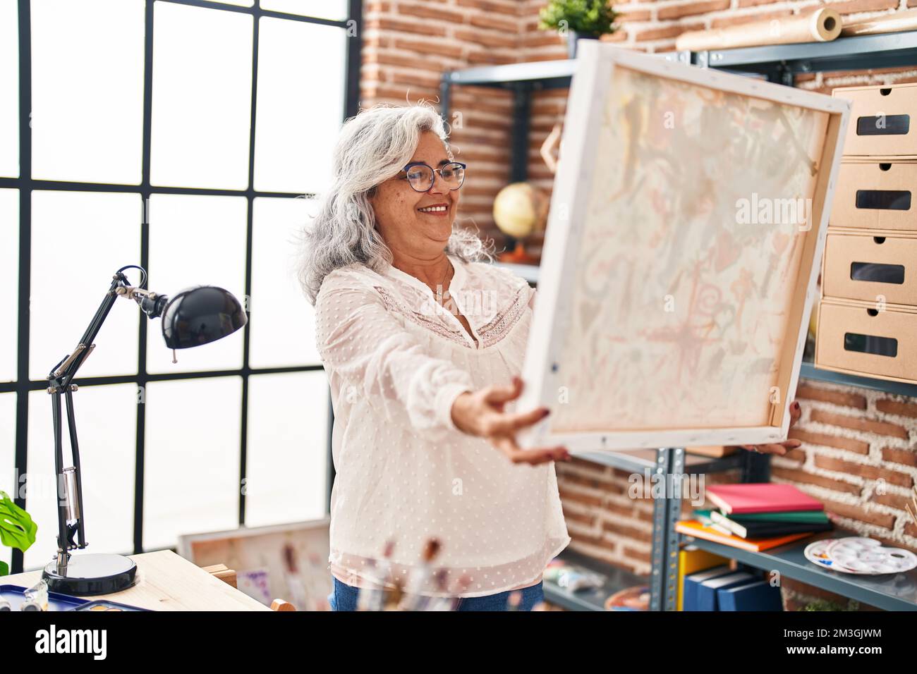 Middle age woman artist smiling confident looking draw at art studio ...