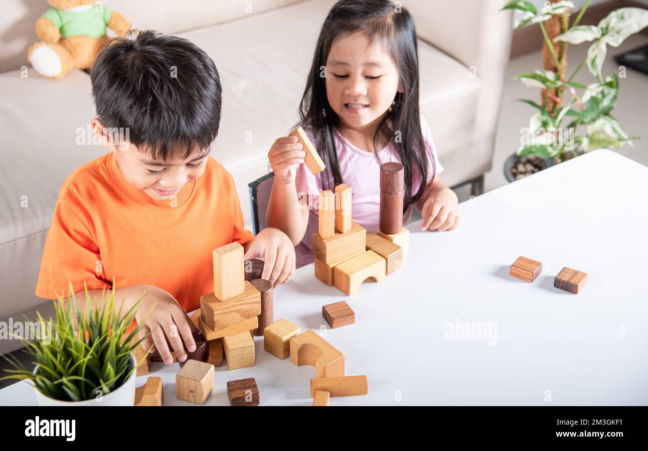 Children boy and girl playing with constructor wooden block building ...