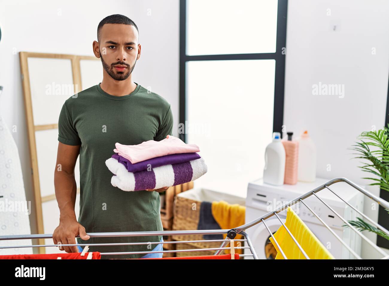 African american man holding folded laundry from clothline thinking ...