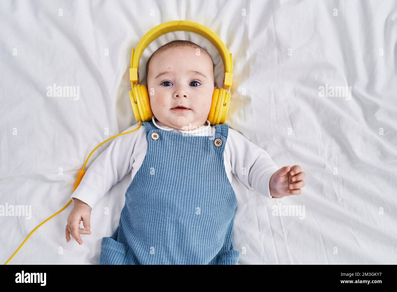 Adorable baby listening to music lying on bed at bedroom Stock Photo ...