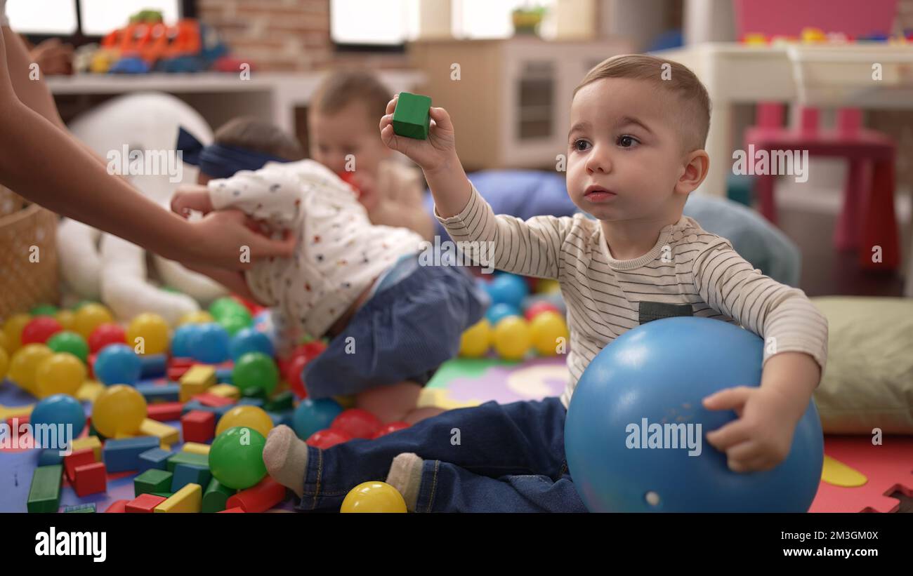 Group of toddlers playing with toys sitting on floor at kindergarten ...