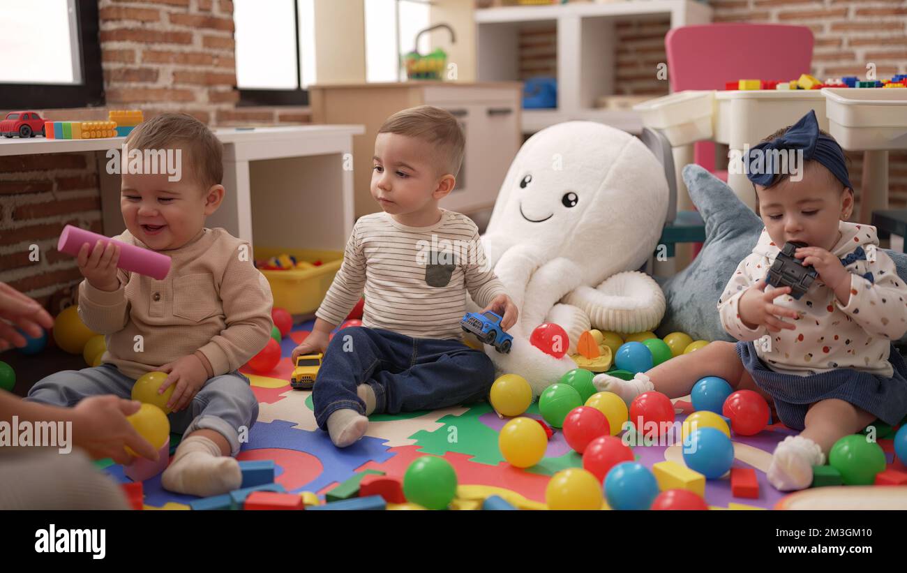 Group of toddlers playing with toys sitting on floor at kindergarten ...