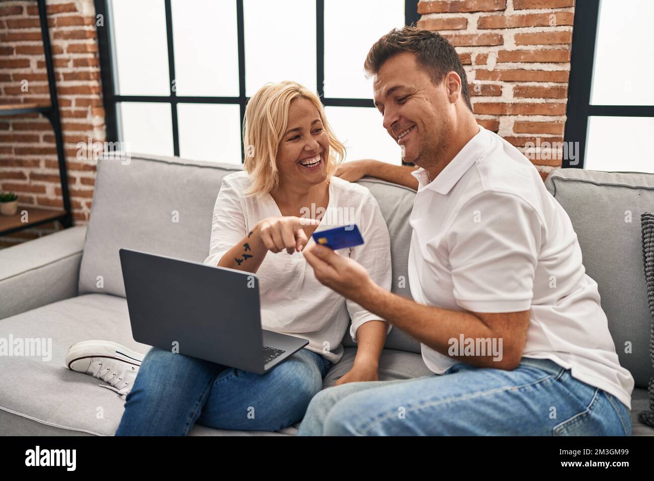 Middle age man and woman using laptop and credit card sitting on sofa ...
