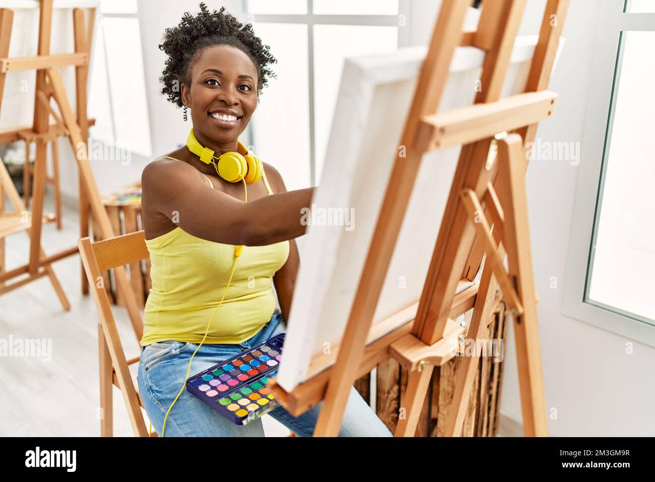 Young african american artist woman using headphones drawing at art ...