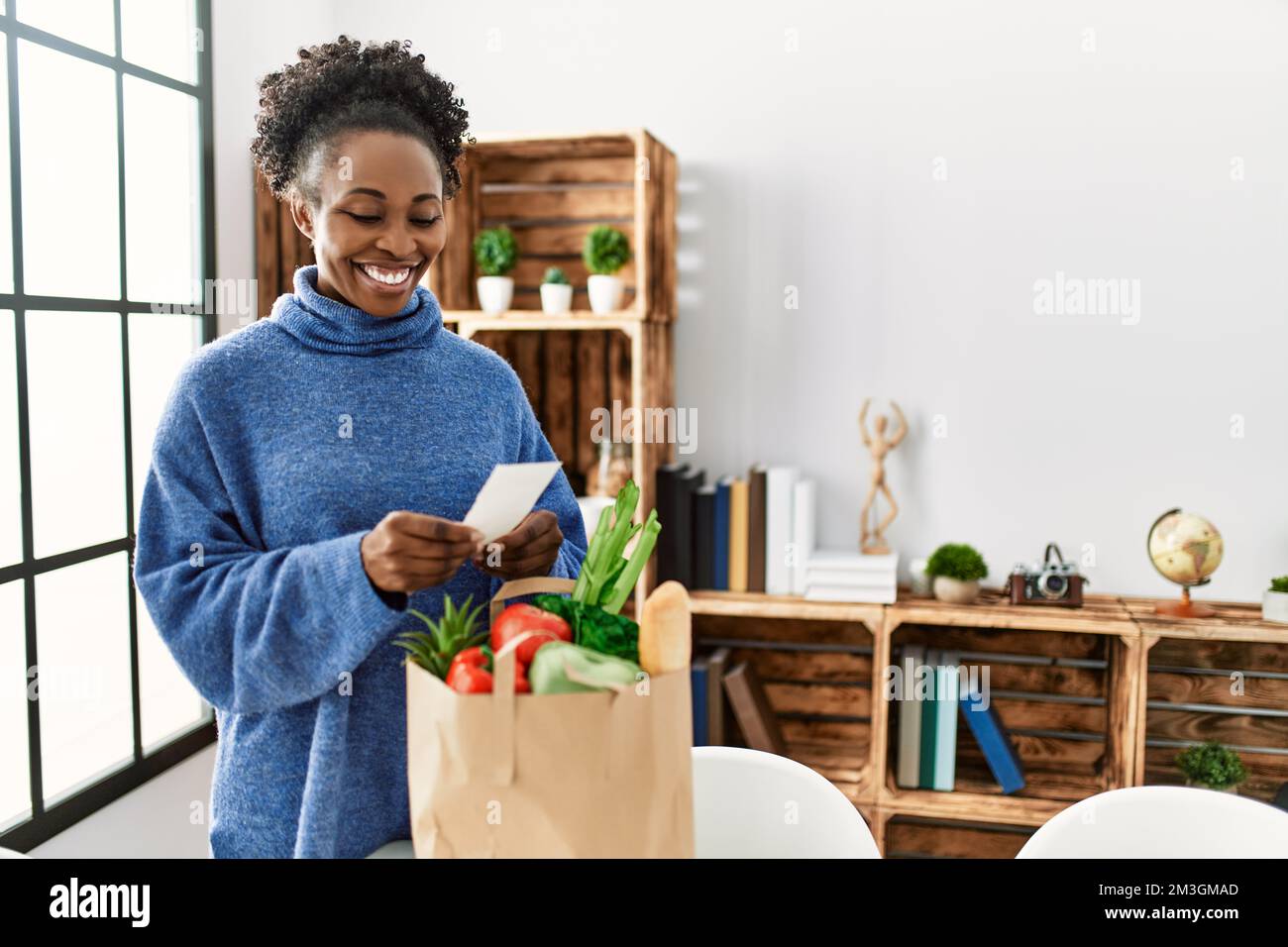 African american woman smiling confident reading food receipt at home ...