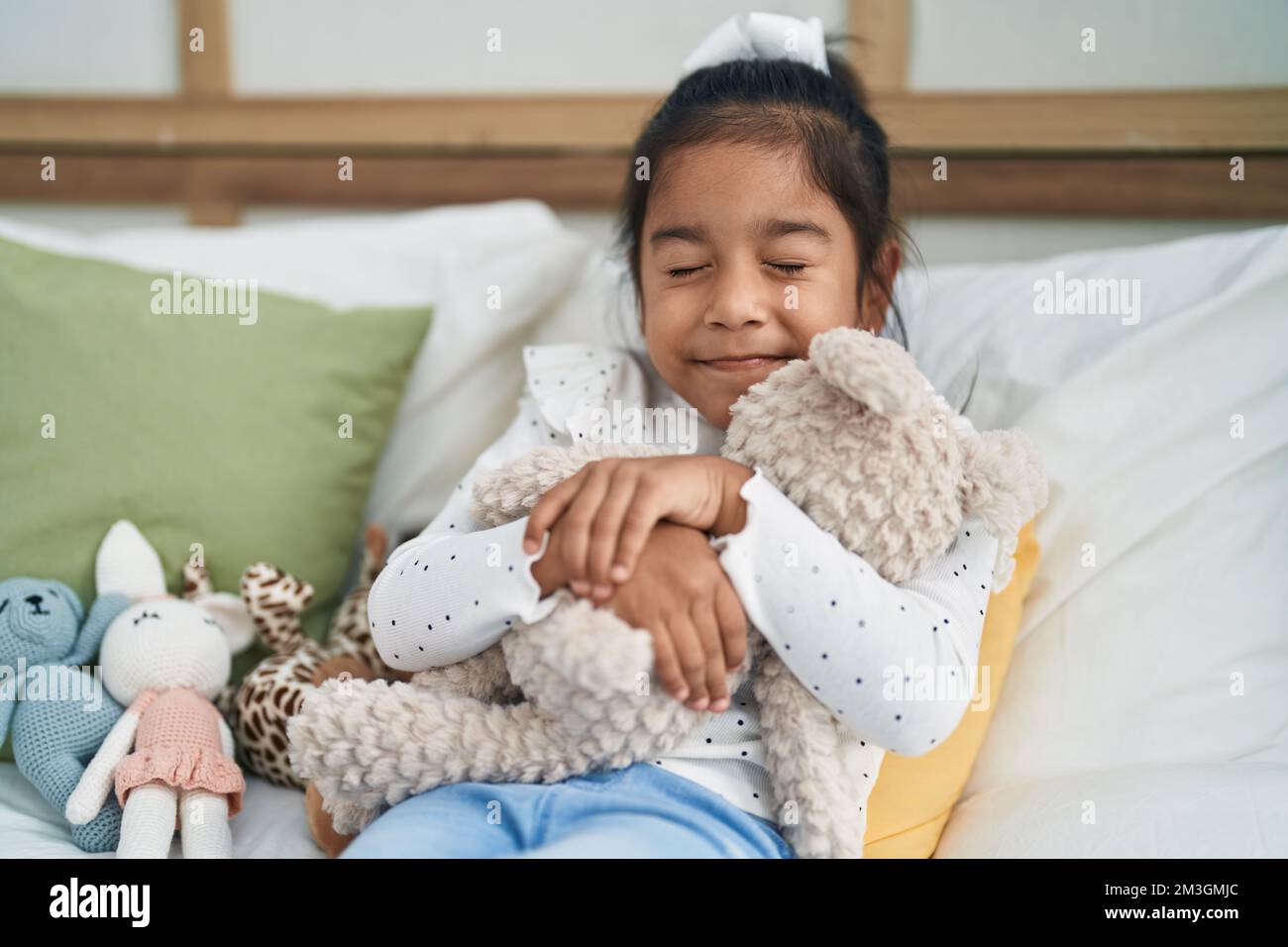 Adorable Hispanic Girl Hugging Teddy Bear Lying On Bed At Bedroom Stock