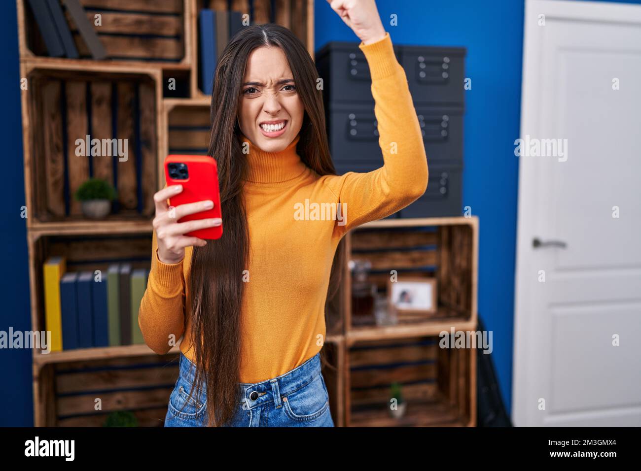 Young brunette woman using smartphone annoyed and frustrated shouting ...