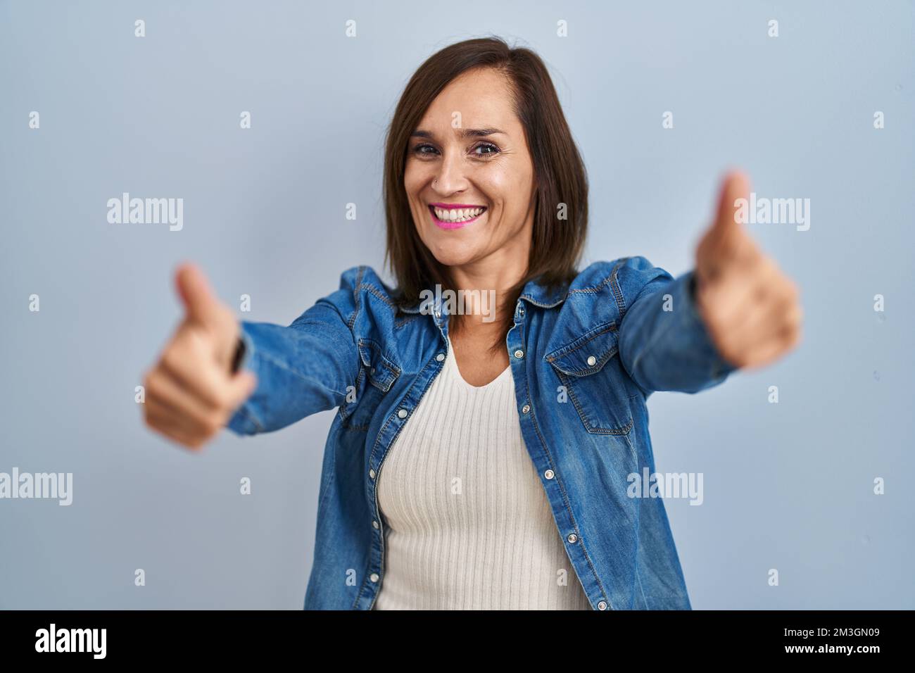 Middle age brunette woman wearing casual denim jacket over isolated ...