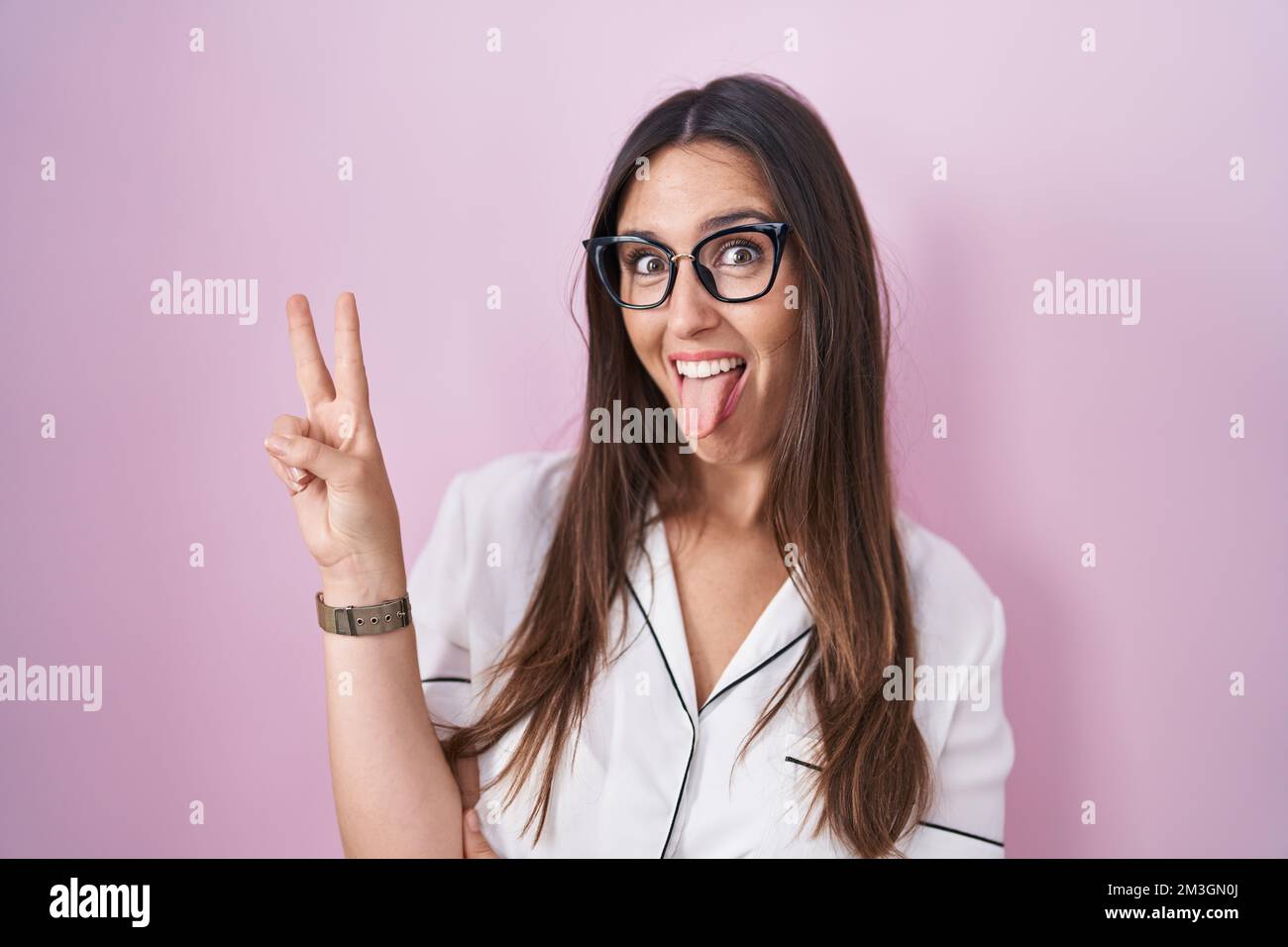 Young brunette woman wearing glasses standing over pink background ...