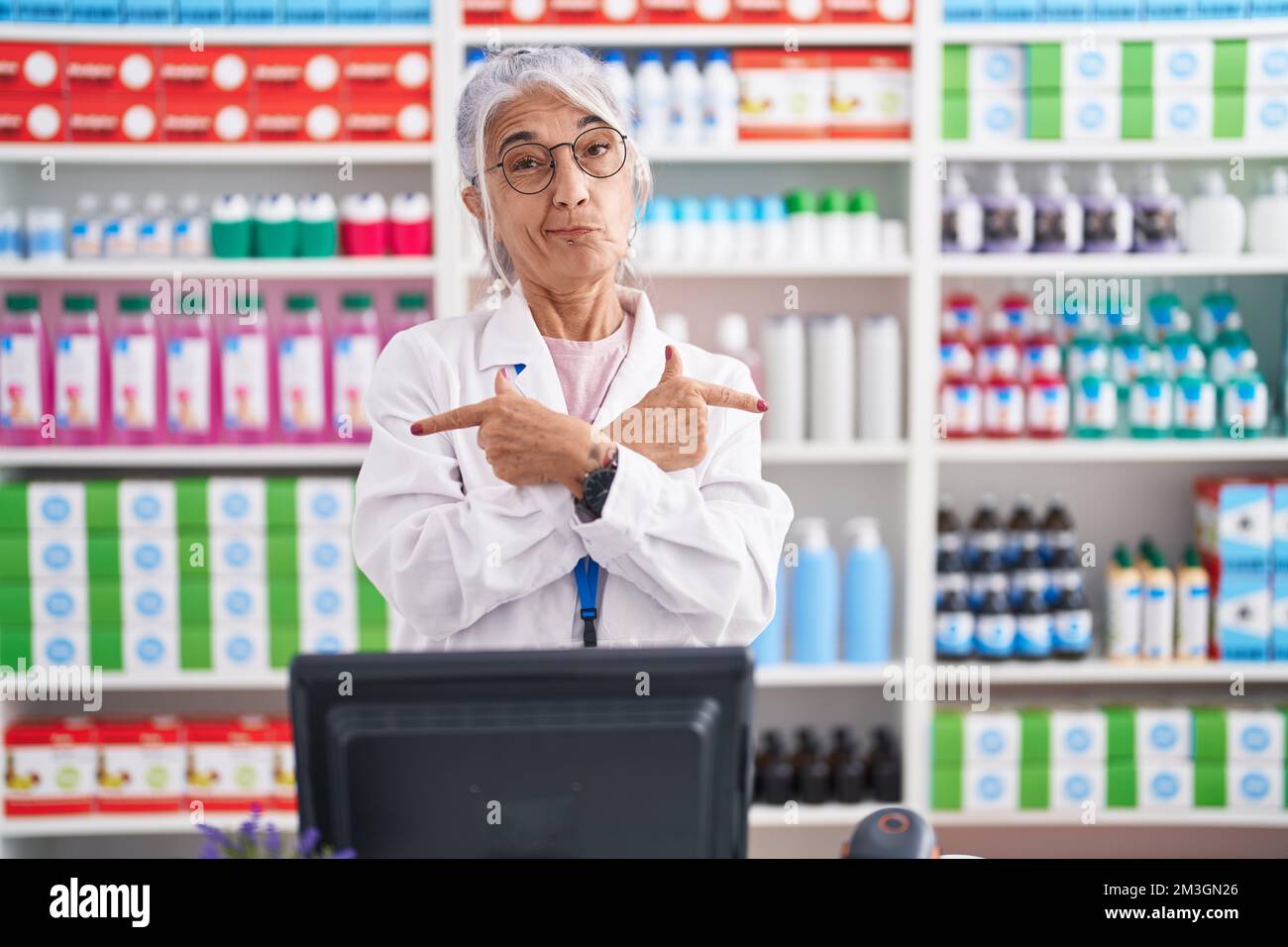 Middle age woman with tattoos working at pharmacy drugstore pointing to ...