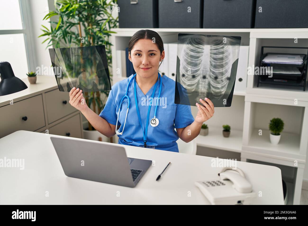Young latin doctor woman holding x-ray smiling with a happy and cool ...