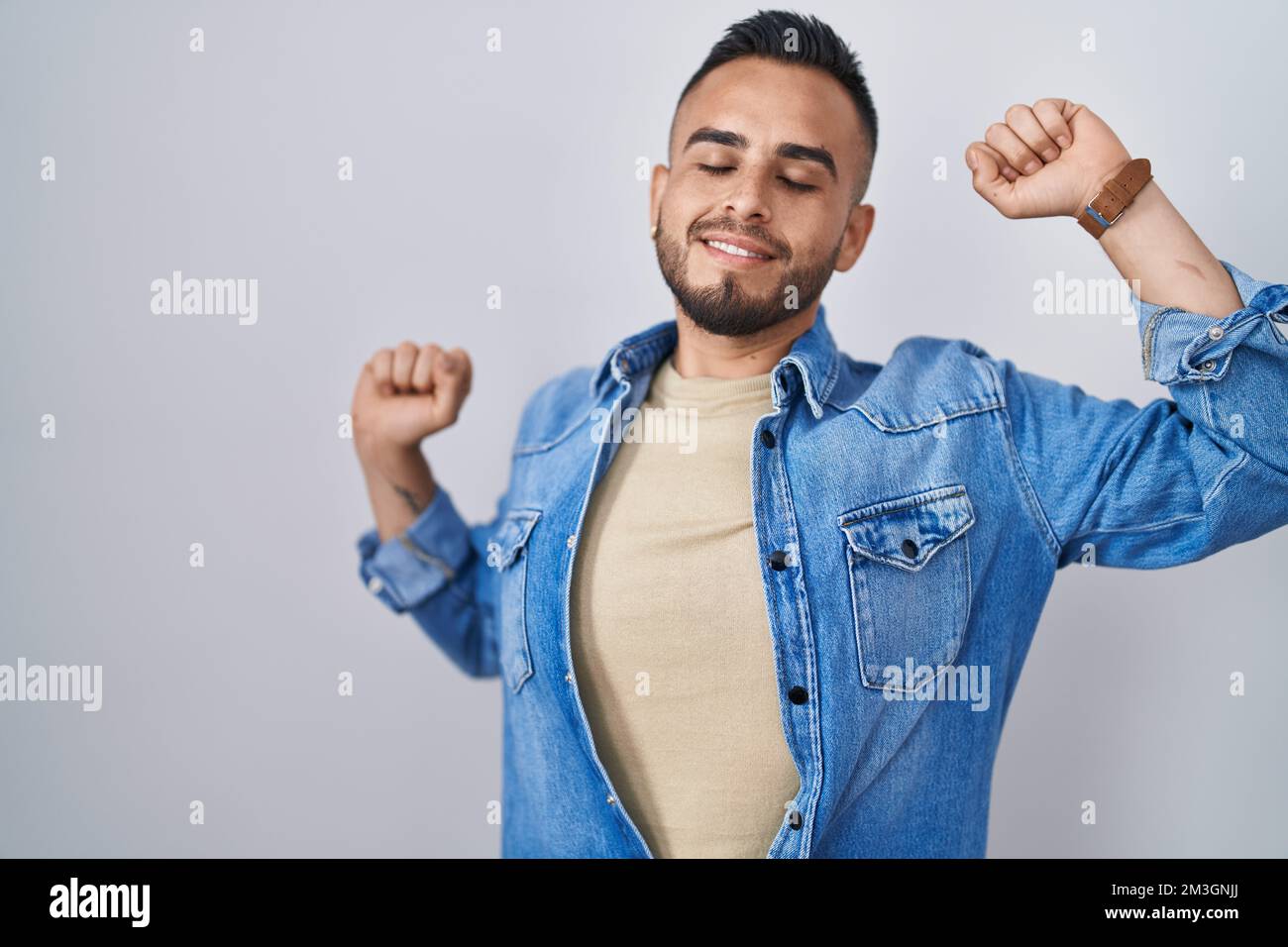 Young hispanic man standing over isolated background stretching back ...