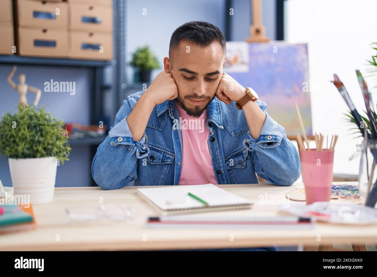 Young hispanic man artist drawing with unhappy expression at art studio ...