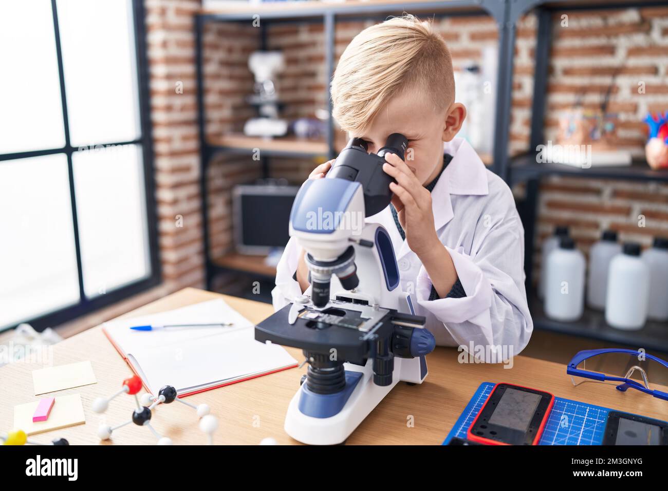 Adorable toddler student using microscope standing at classroom Stock ...