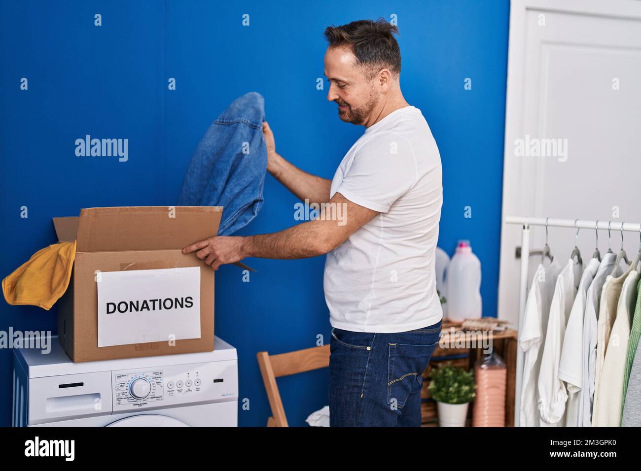 Young caucasian man smiling confident putting clothes on donations ...