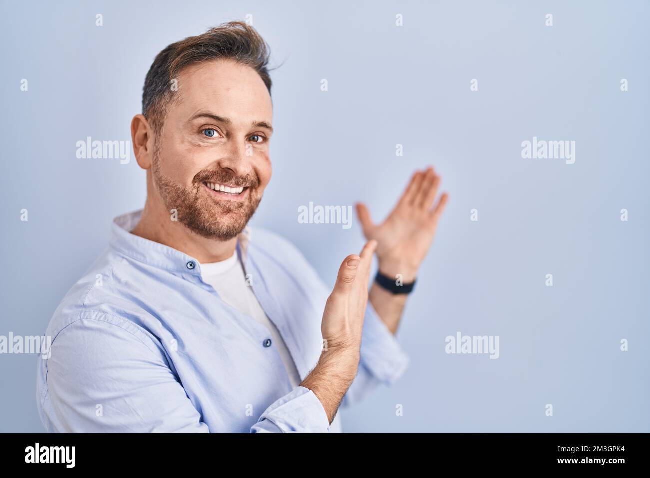 Middle age caucasian man standing over blue background inviting to ...