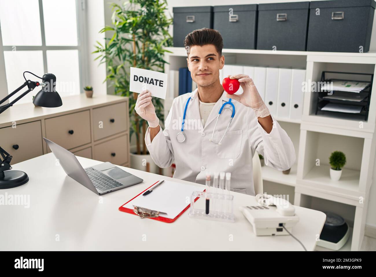 Young hispanic doctor man supporting organs donations smiling looking ...