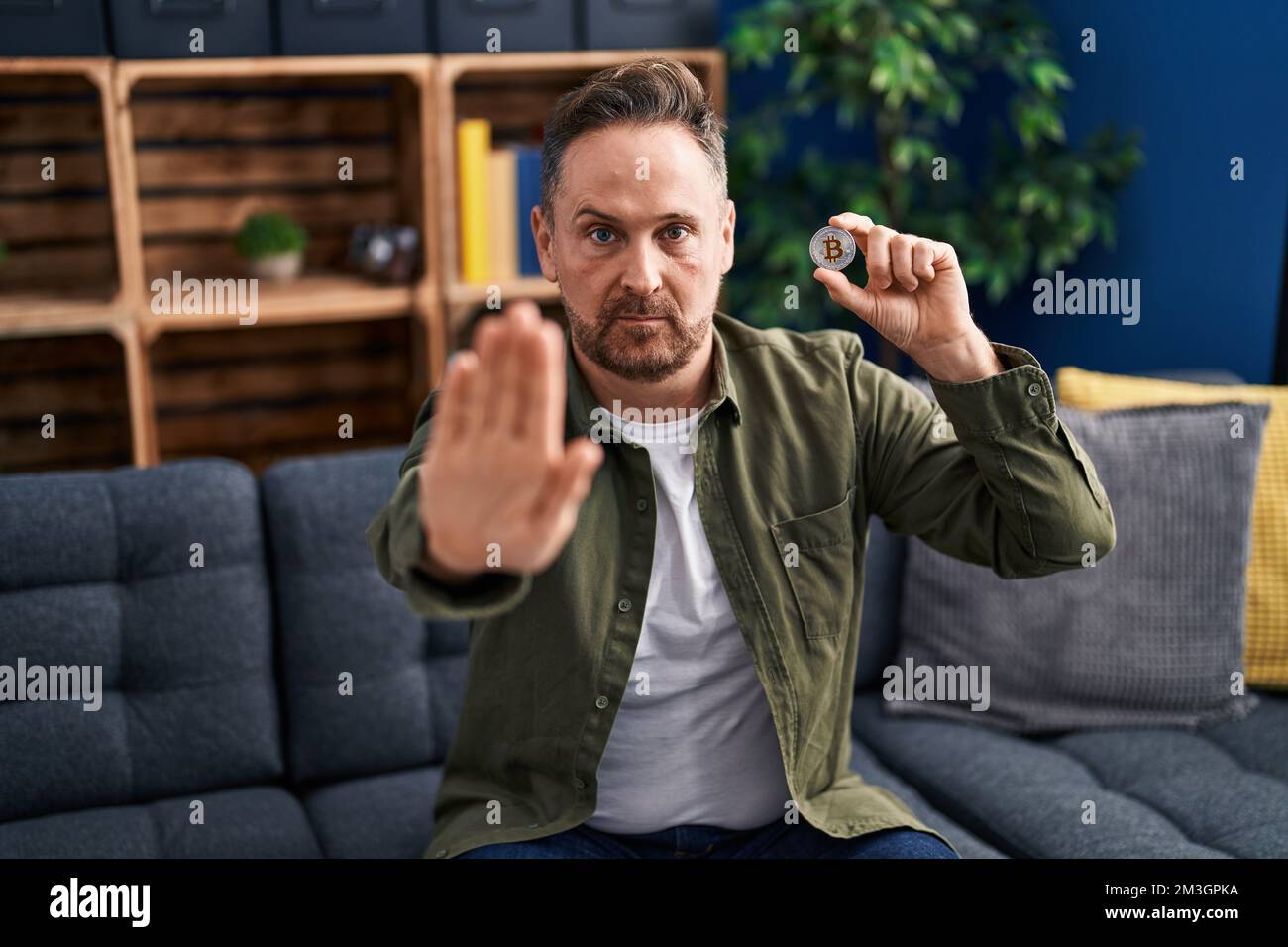 Middle age caucasian man holding virtual currency bitcoin with open ...