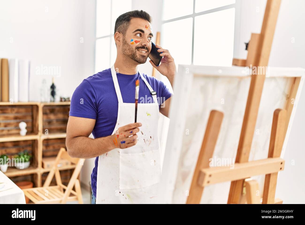 Young hispanic man smiling confident talking on the smartphone drawing ...