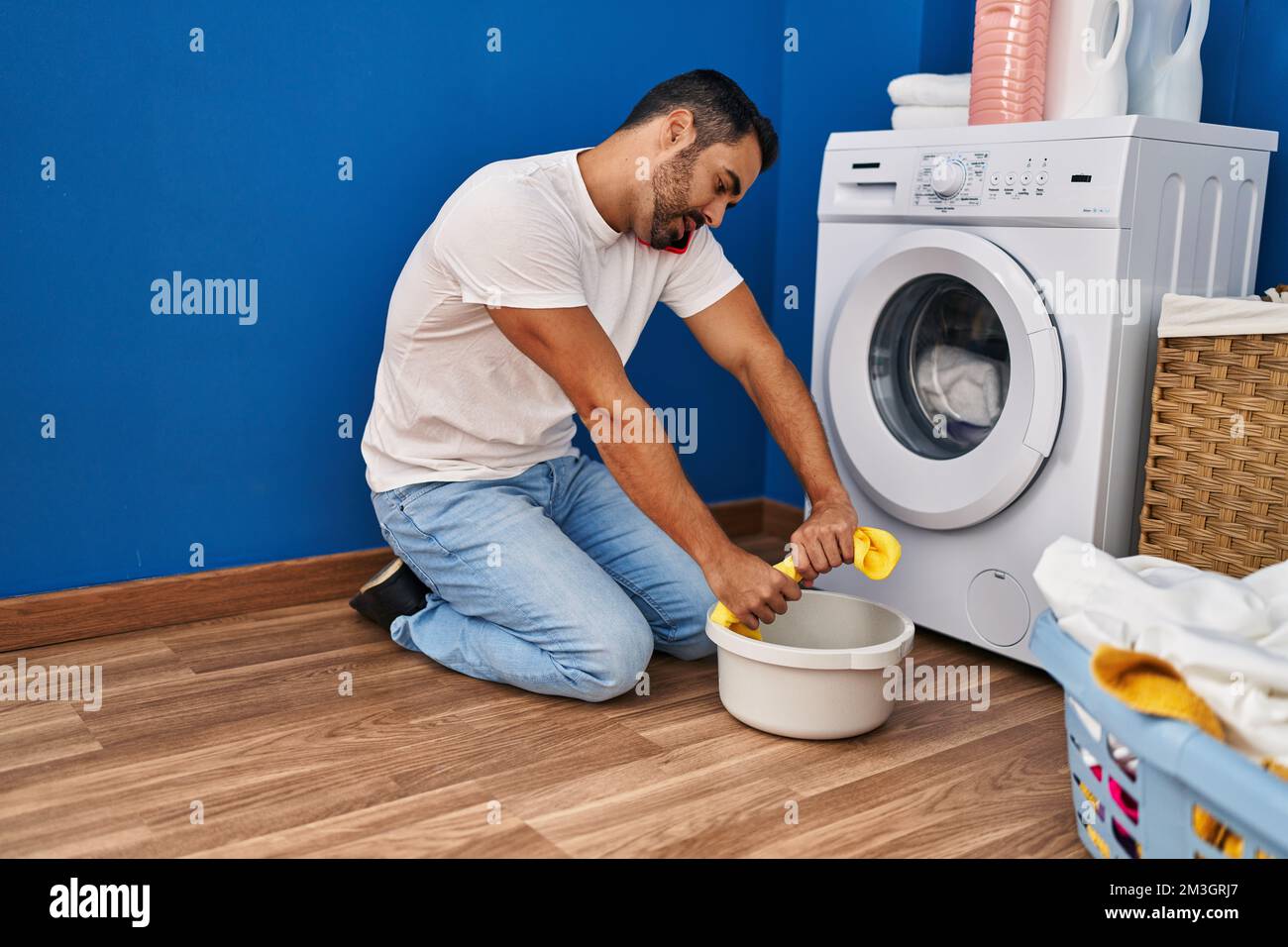 Young hispanic man talking on the smartphone wringing out rag at ...