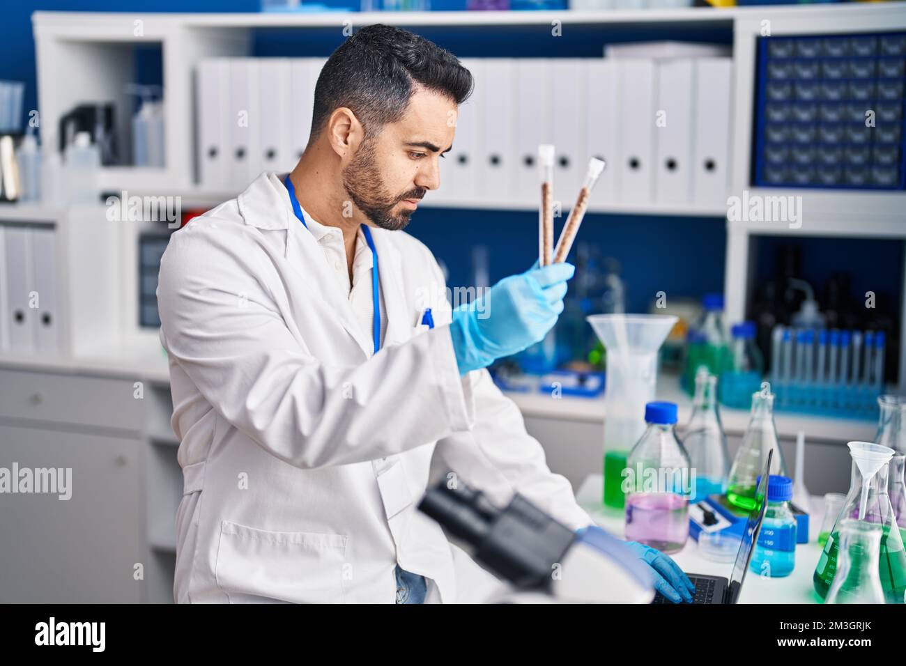 Young hispanic man scientist holding test tubes at laboratory Stock ...