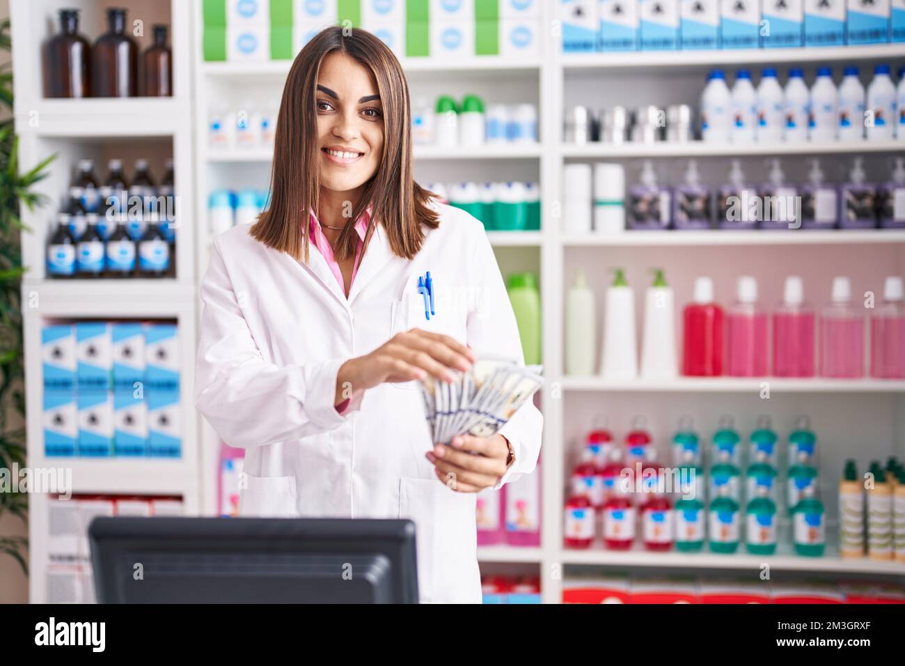 Young beautiful hispanic woman pharmacist counting dollars using ...