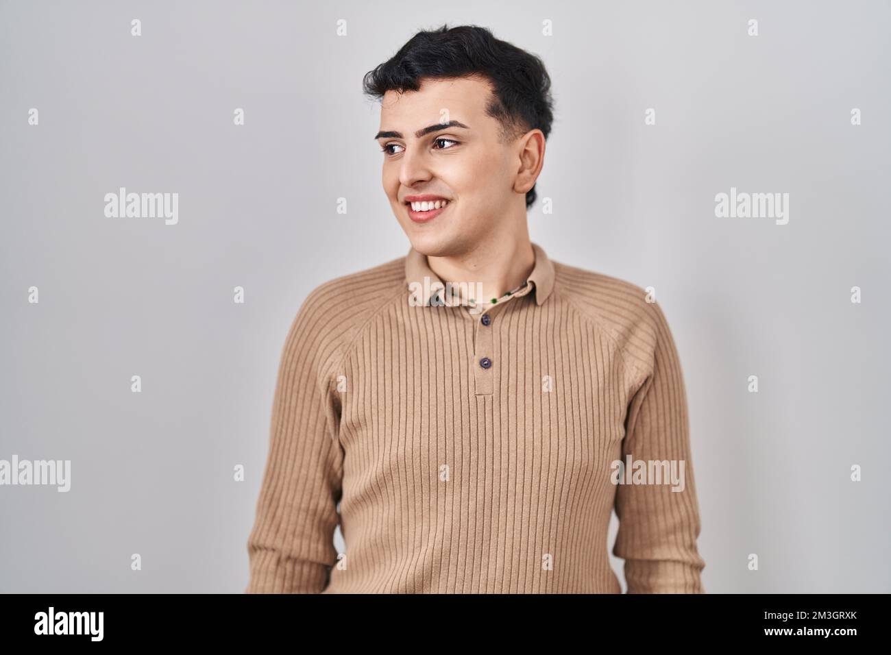 Non binary person standing over isolated background looking away to ...