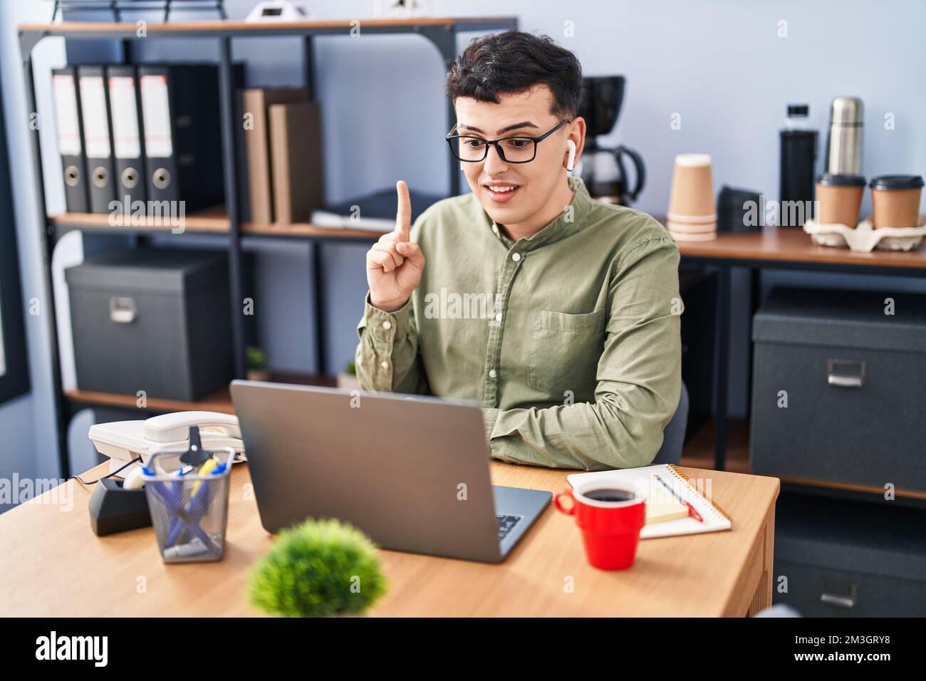 Non binary person working at the office wearing glasses smiling with an ...