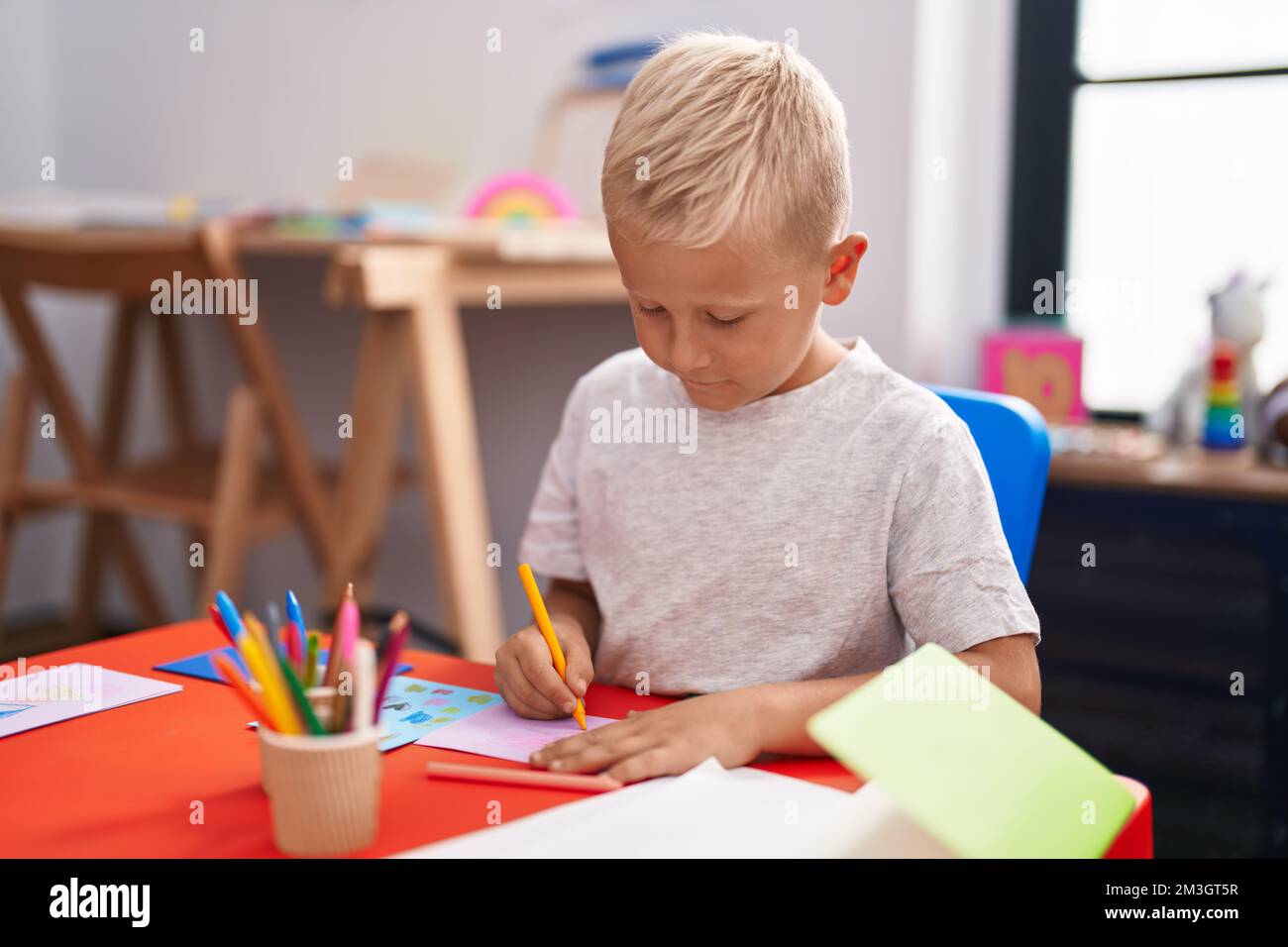 Adorable toddler student drawing on notebook sitting on table at ...
