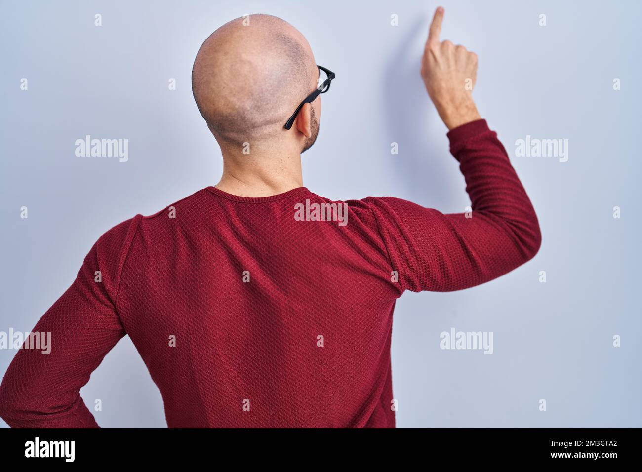 Young bald man with beard standing over white background wearing ...