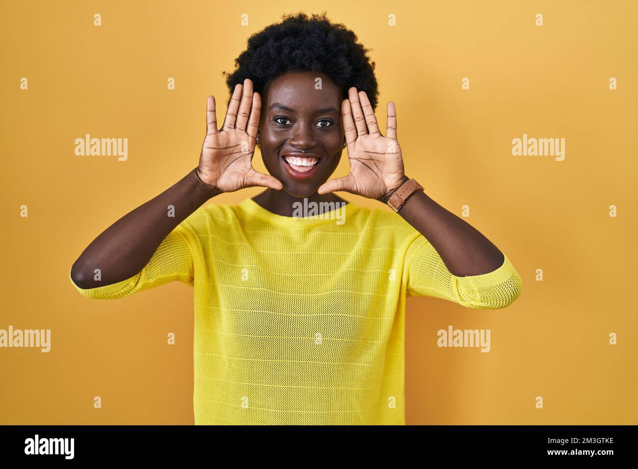 African young woman standing over yellow studio smiling cheerful ...