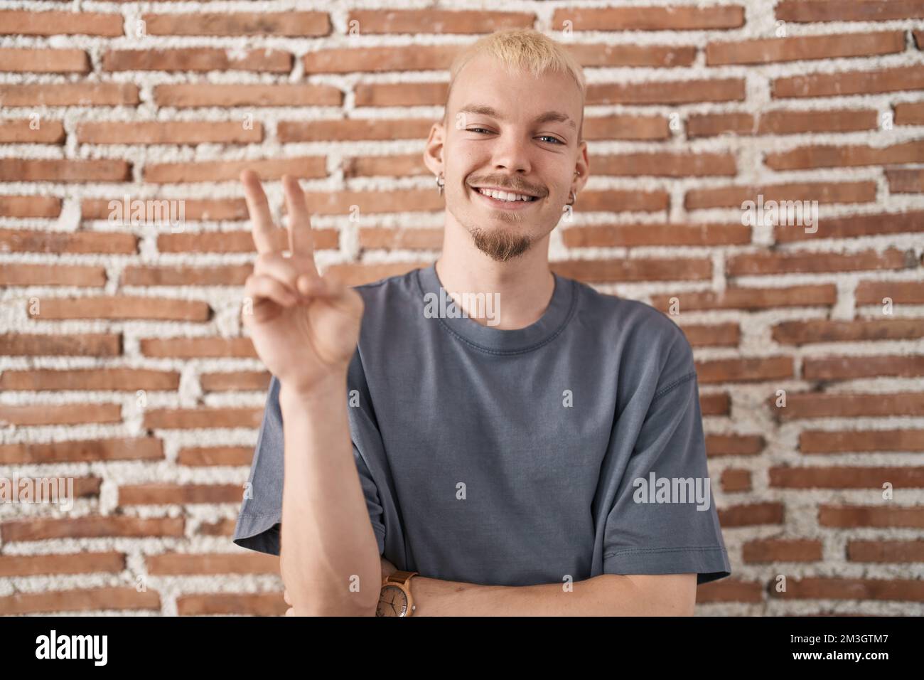 Young caucasian man standing over bricks wall smiling with happy face ...