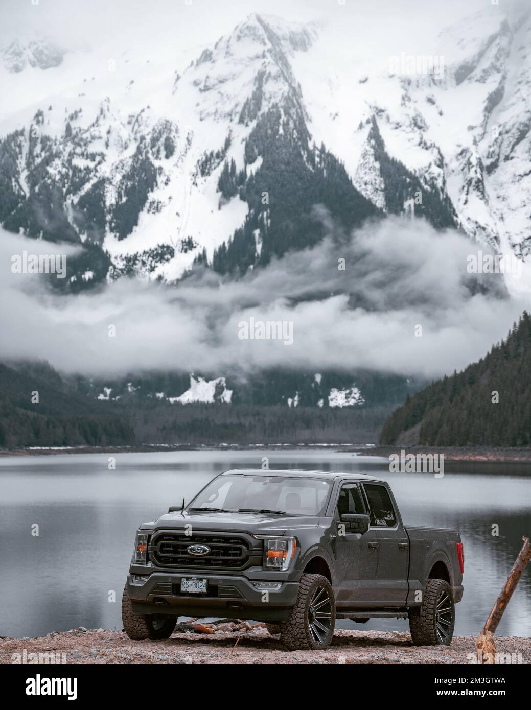 A vertical shot of a Ford F-150 at the shore of a lake on the ...