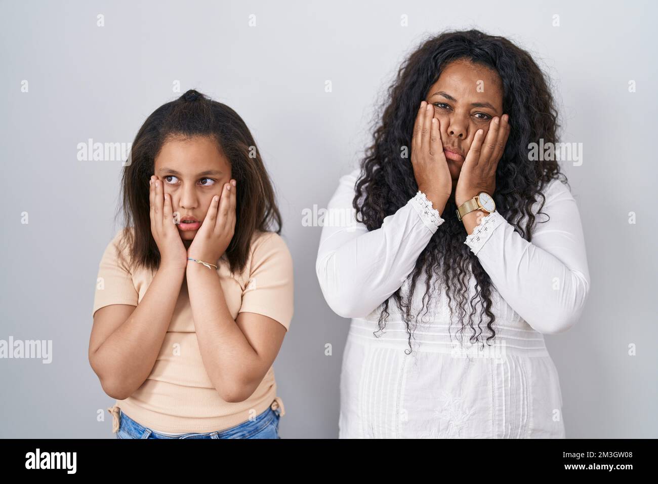 Mother and young daughter standing over white background tired hands ...
