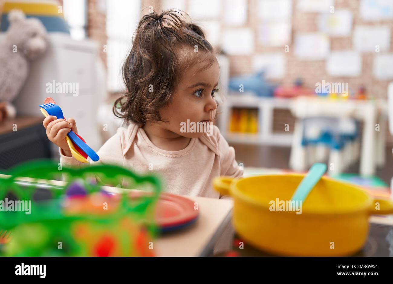 Adorable hispanic girl playing with play kitchen standing at ...