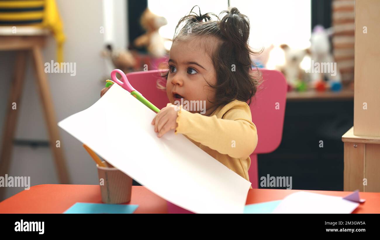 Adorable hispanic girl student cutting paper at kindergarten Stock ...