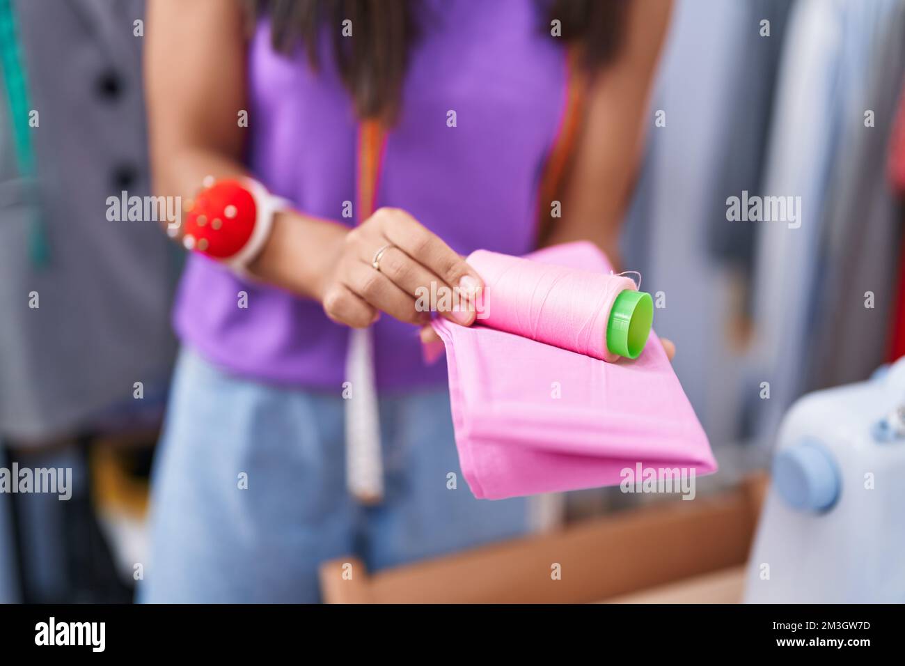 Young beautiful hispanic woman tailor holding thread and cloth at ...