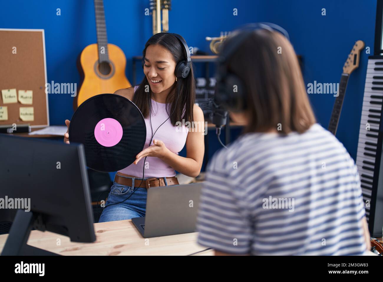 Two women musicians listening to music holding vinyl disc at music ...