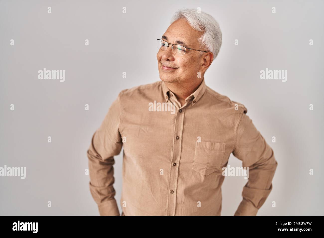Hispanic senior man wearing glasses smiling looking to the side and ...