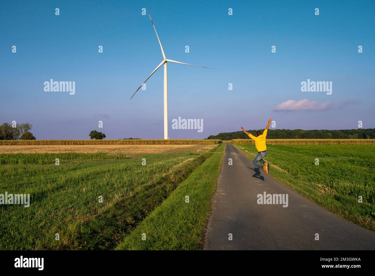 A young guy jumping in from of a wind turbine Stock Photo - Alamy