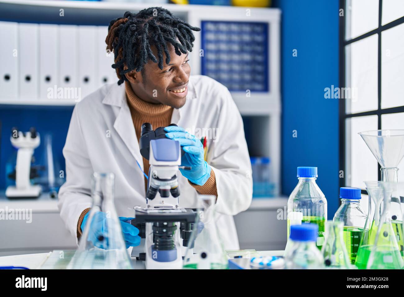 African american man scientist using microscope at laboratory Stock Photo - Alamy