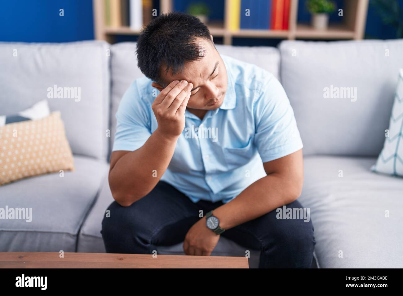 Young chinese man stressed sitting on sofa at home Stock Photo - Alamy
