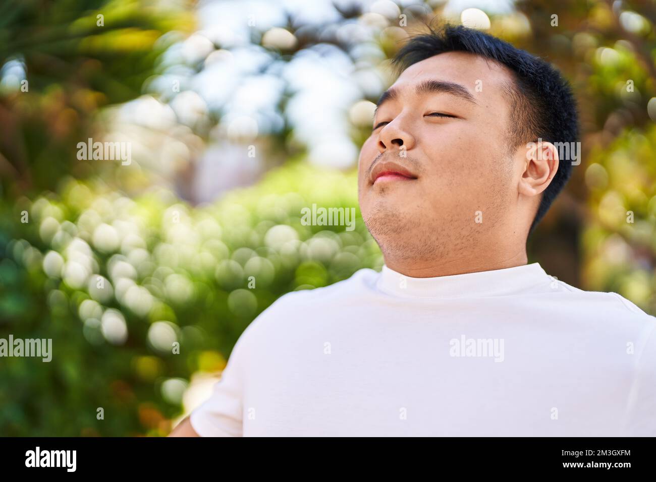 Young chinese man breathing standing at park Stock Photo - Alamy