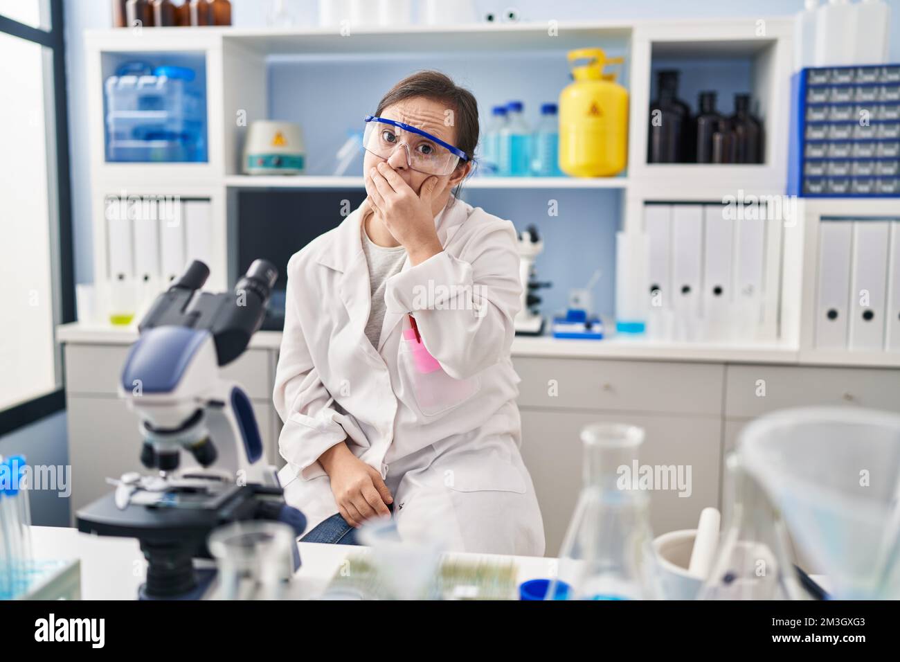Hispanic girl with down syndrome working at scientist laboratory bored ...