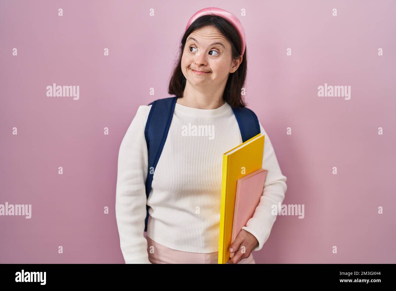 Woman with down syndrome wearing student backpack and holding books ...
