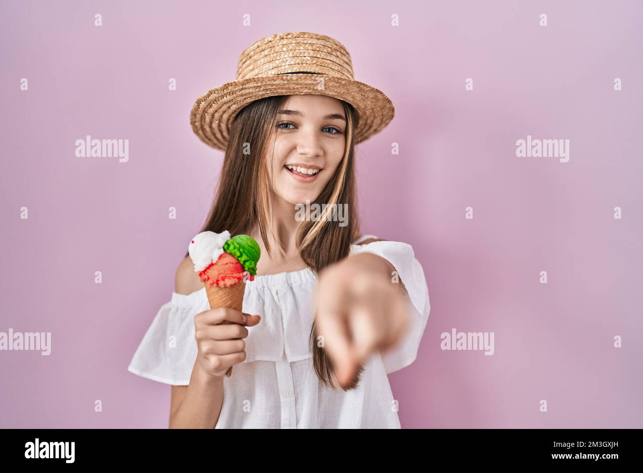 Teenager girl holding ice cream pointing to you and the camera with ...